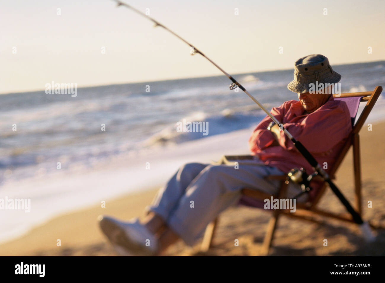 Senior man relaxing in a chair with a fishing rod on the beach Stock ...