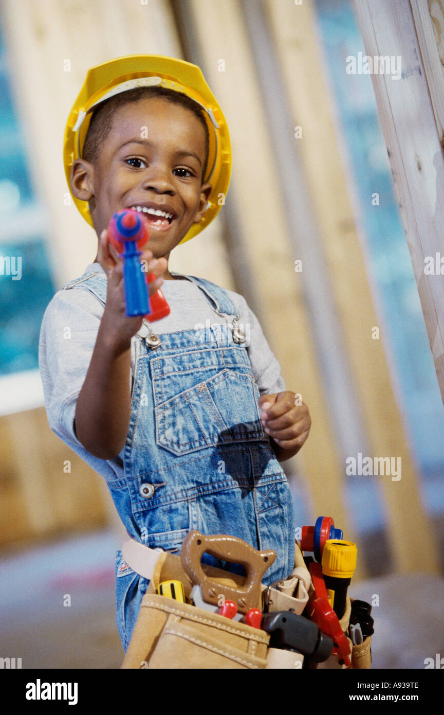 Portrait of a boy dressed as a construction worker holding a toy drill ...