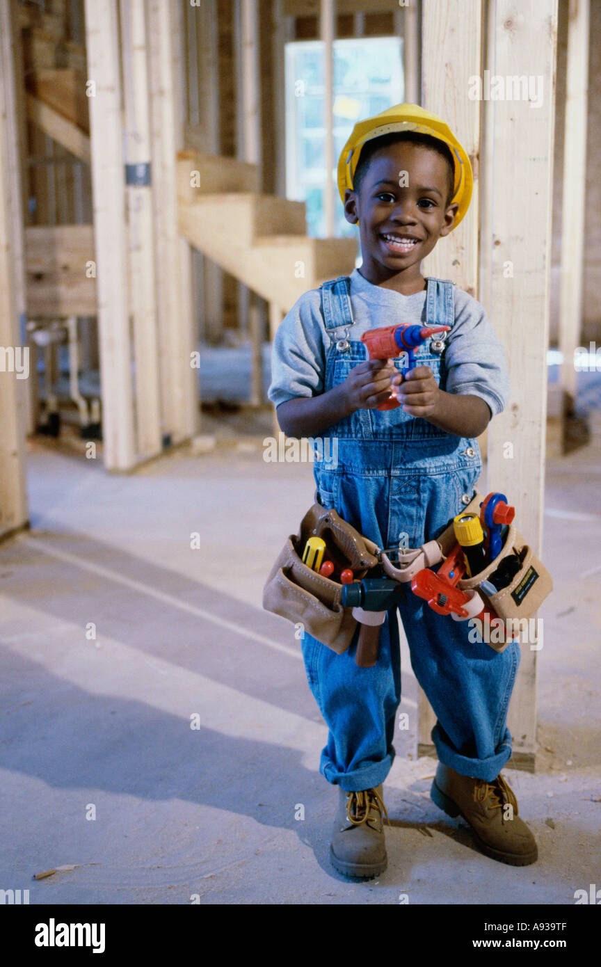 Portrait of a boy dressed as a construction worker holding a toy drill ...