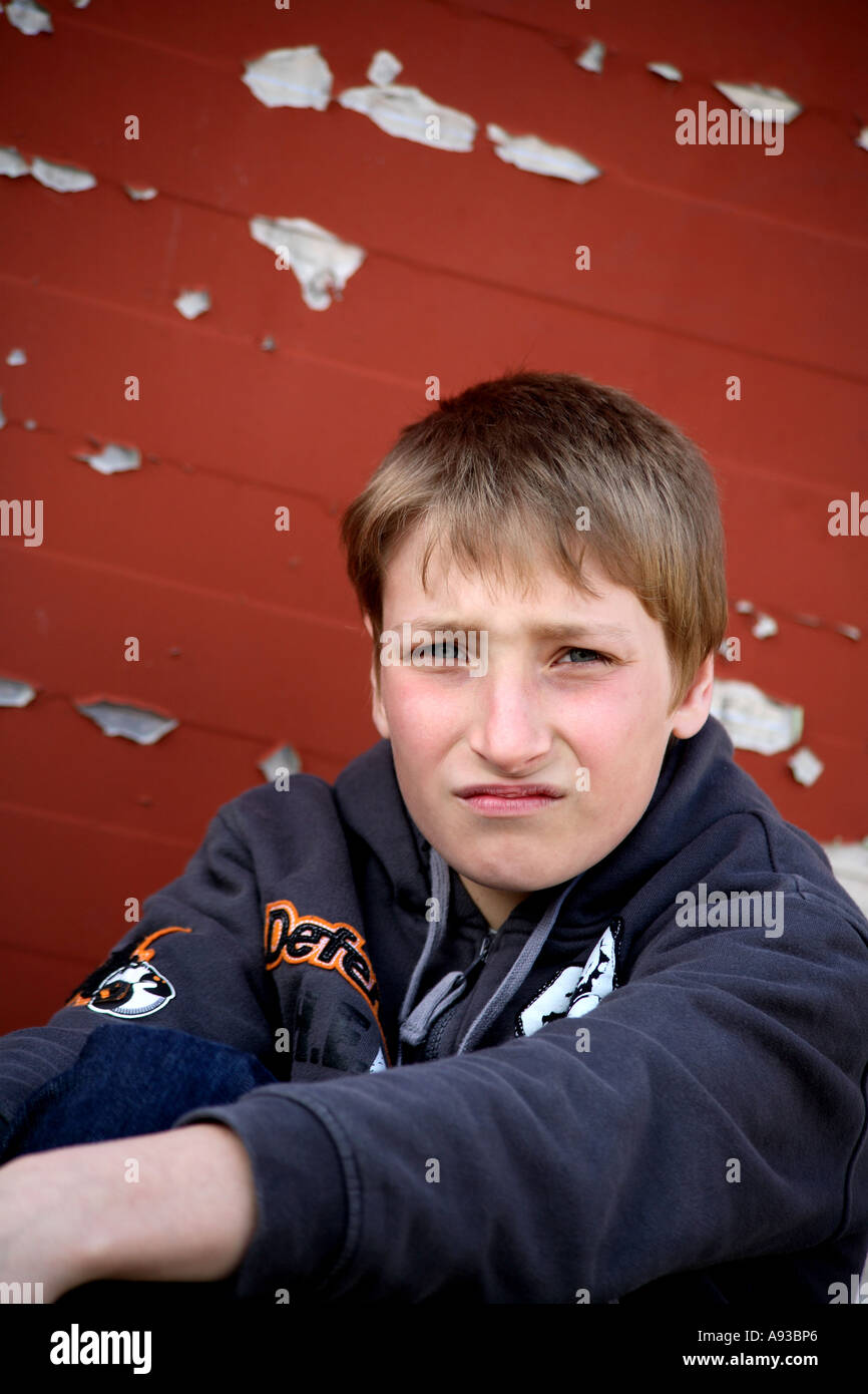 Vertical close up portrait of young teenage lad sitting alone by ...