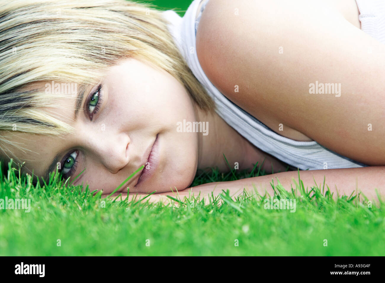 Young woman lying on grass smiling green eyes Stock Photo - Alamy