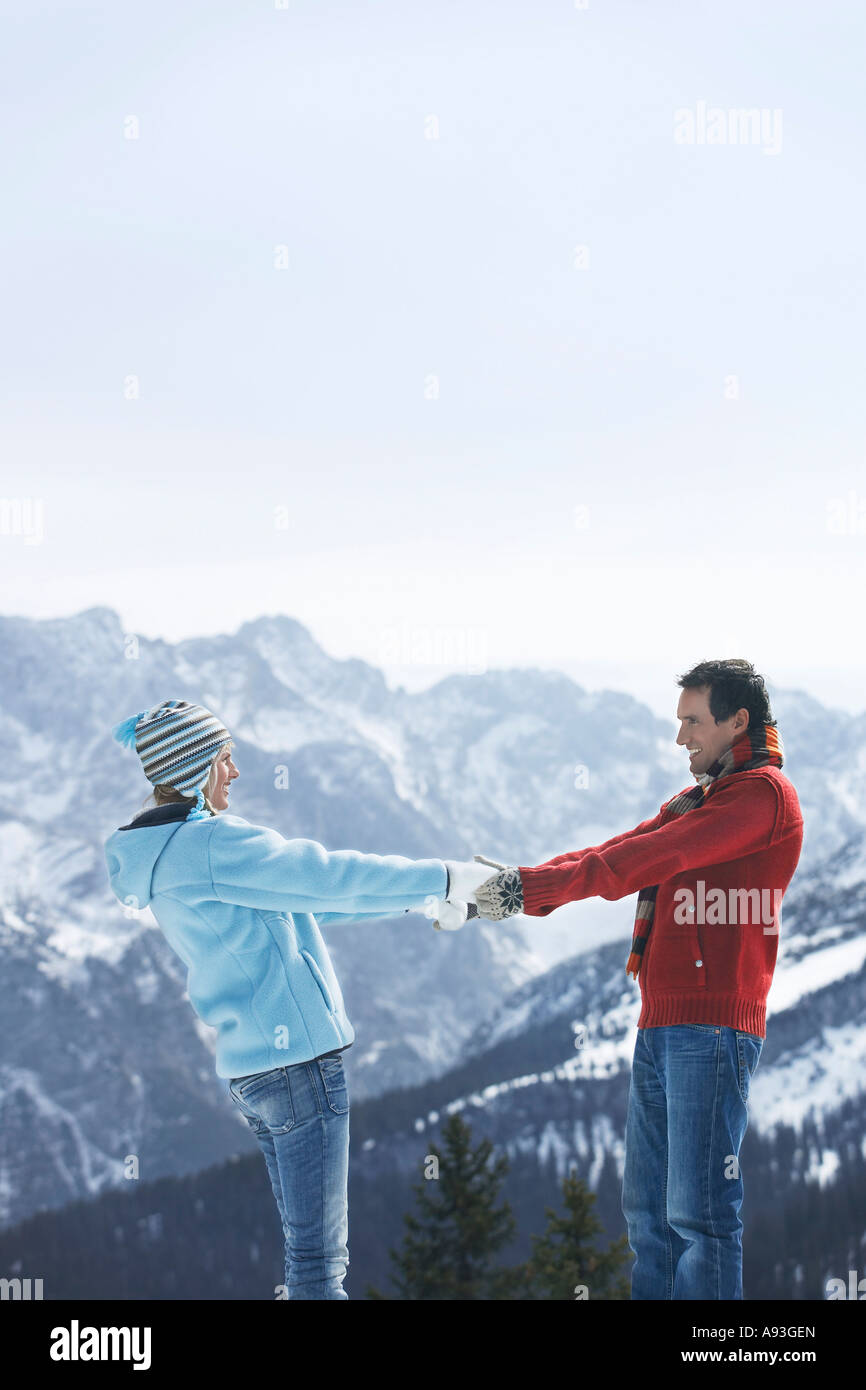 Couple holding hands standing face to face in mountains, side view ...