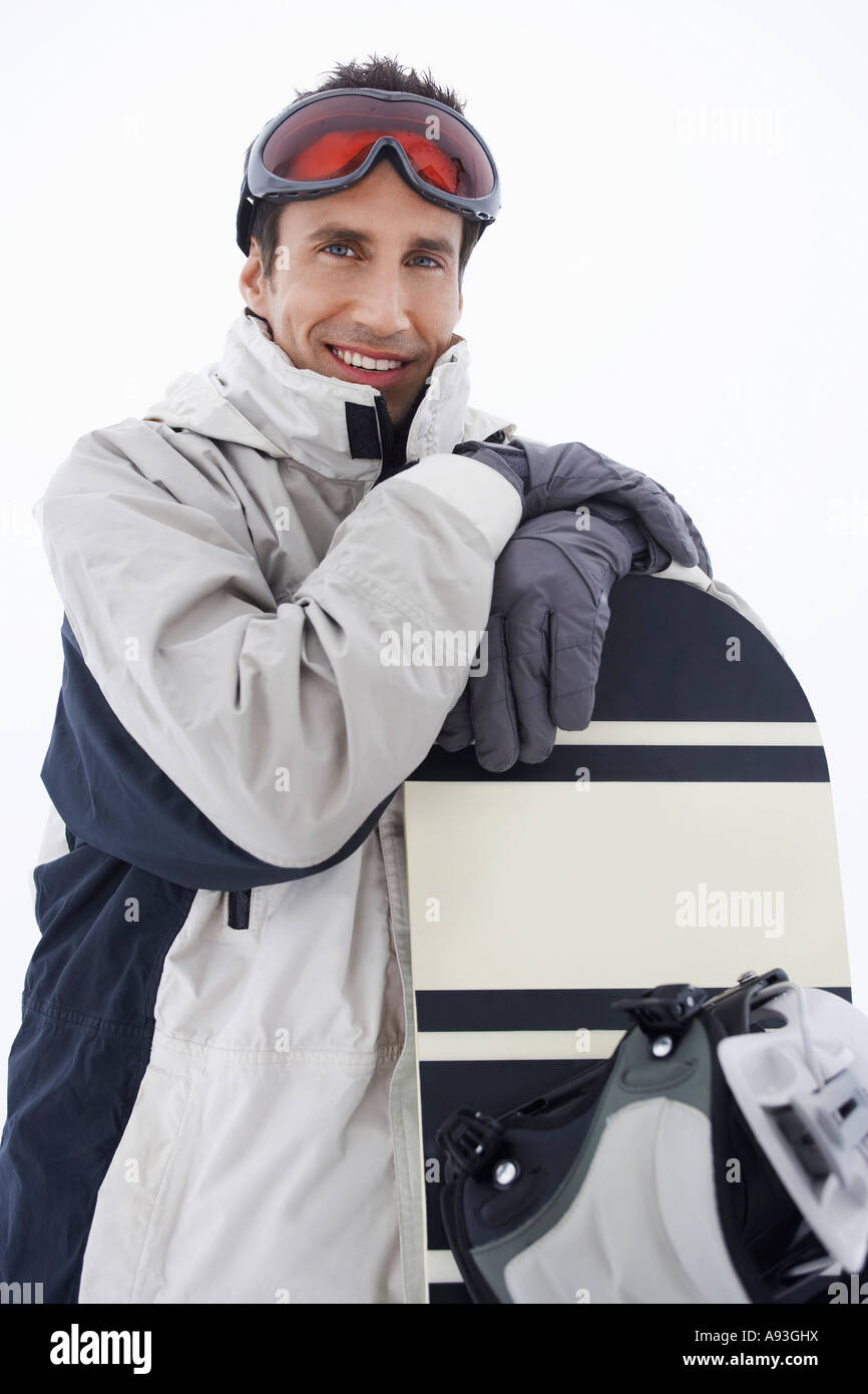 Man wearing ski goggles, holding snowboard, portrait Stock Photo - Alamy