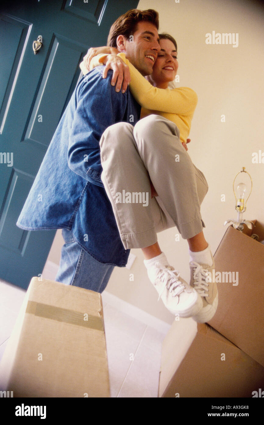 Side profile of a young man carrying a young woman into their new house ...
