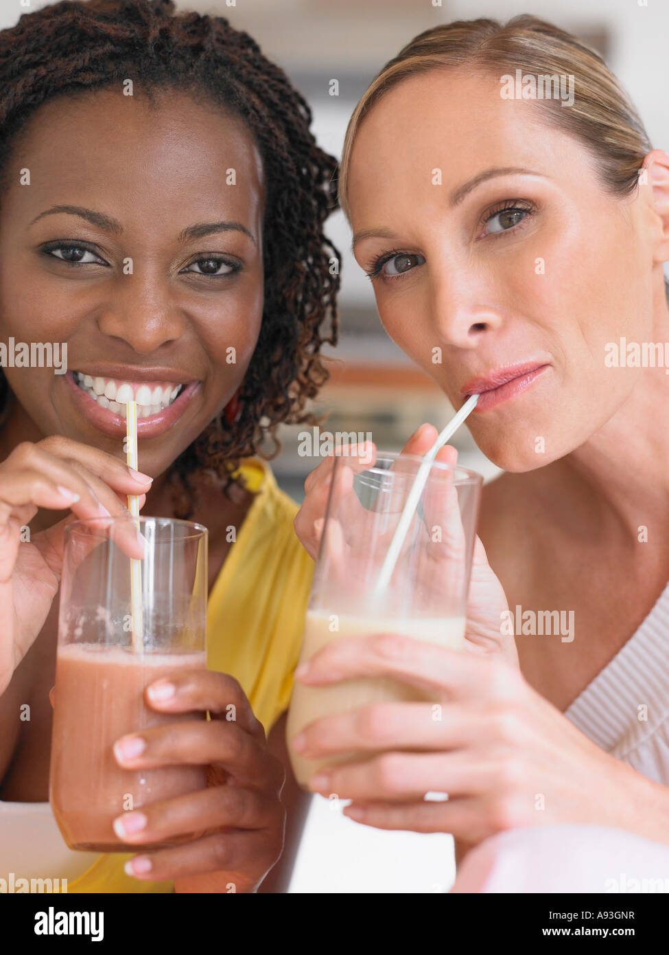 Two women drinking milkshake, portrait Stock Photo - Alamy