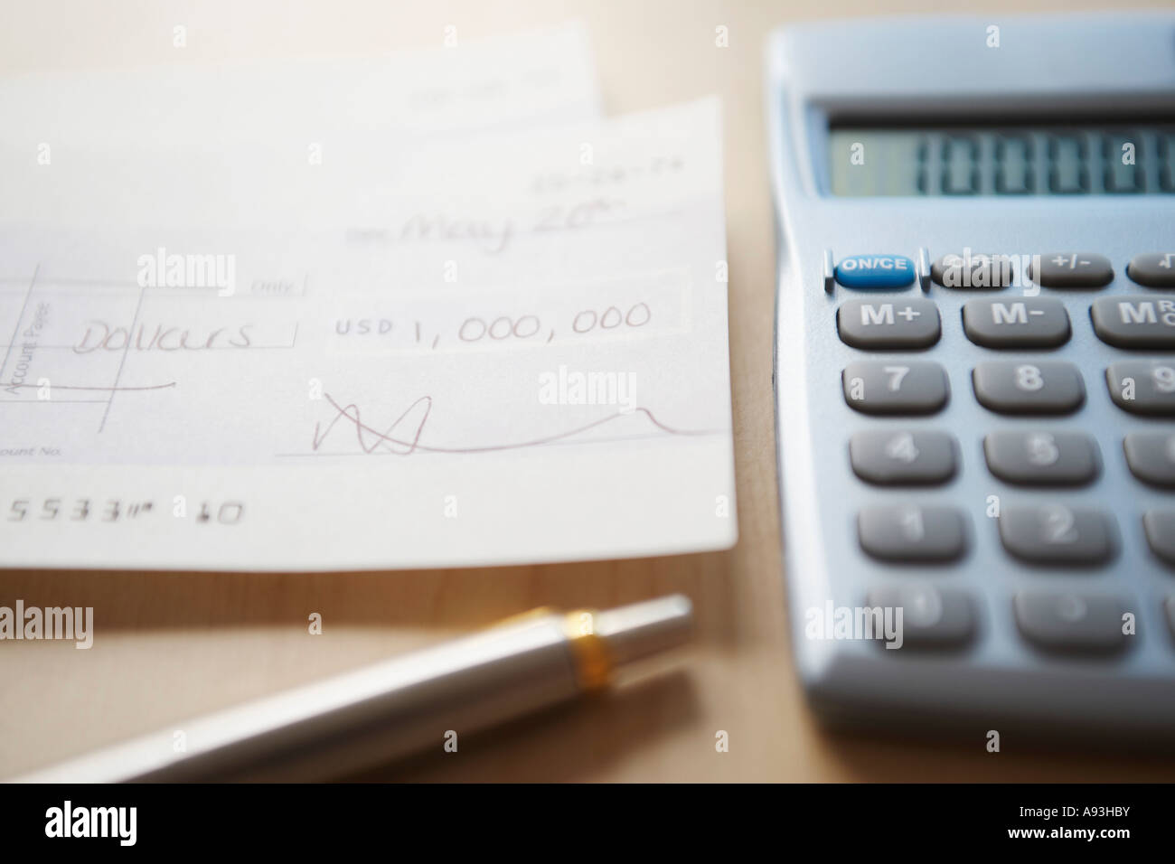 Calculator; pen and filled cheque on wooden table Stock Photo - Alamy