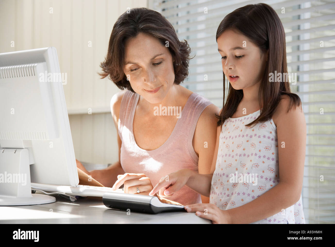 Daughter helping mother use computer at home Stock Photo - Alamy