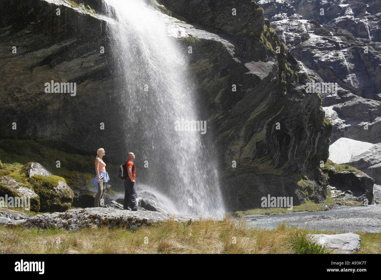 Hikers standing under waterfall at river Stock Photo - Alamy