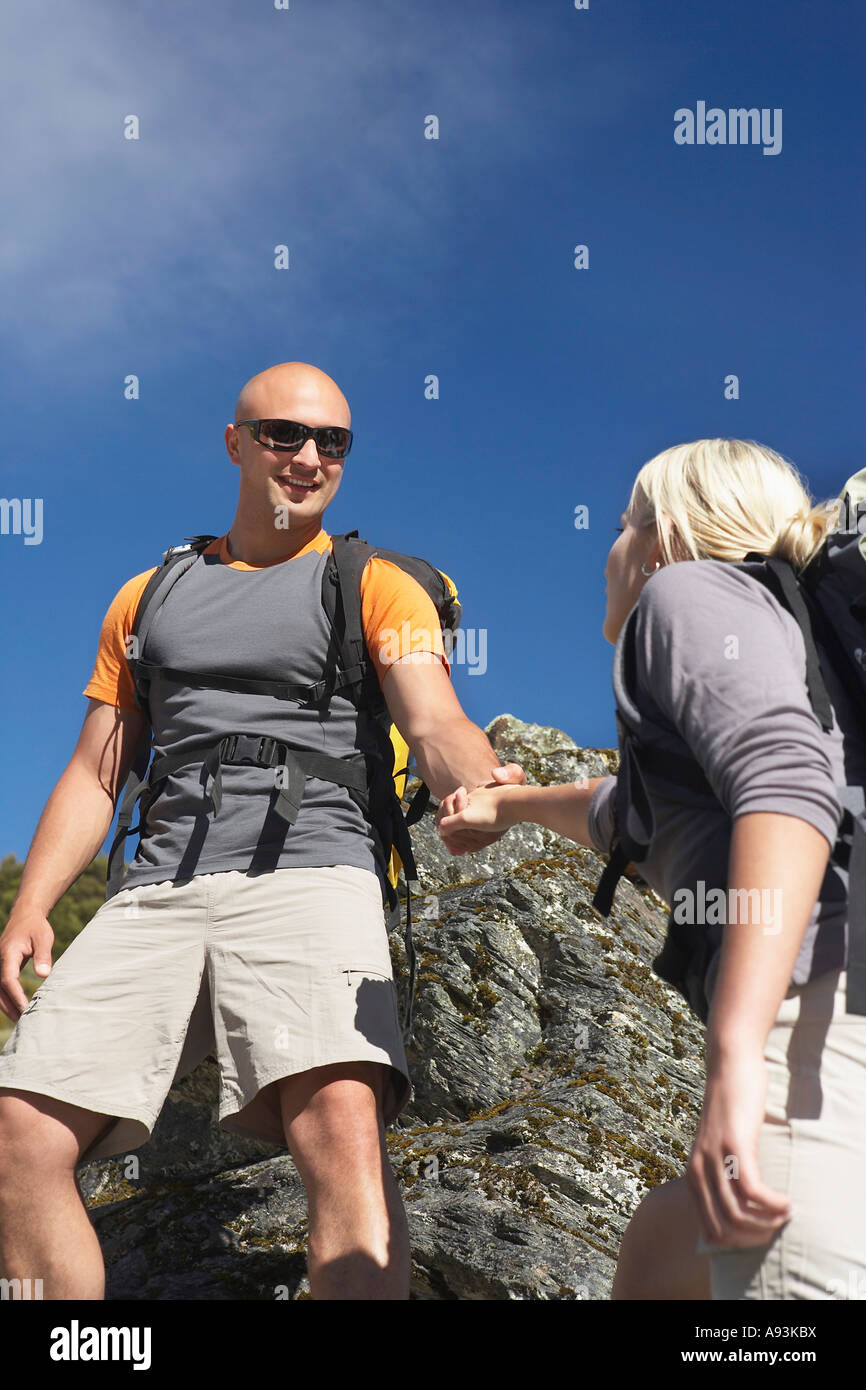 Man helping woman climb onto boulder in middle of river Stock Photo - Alamy