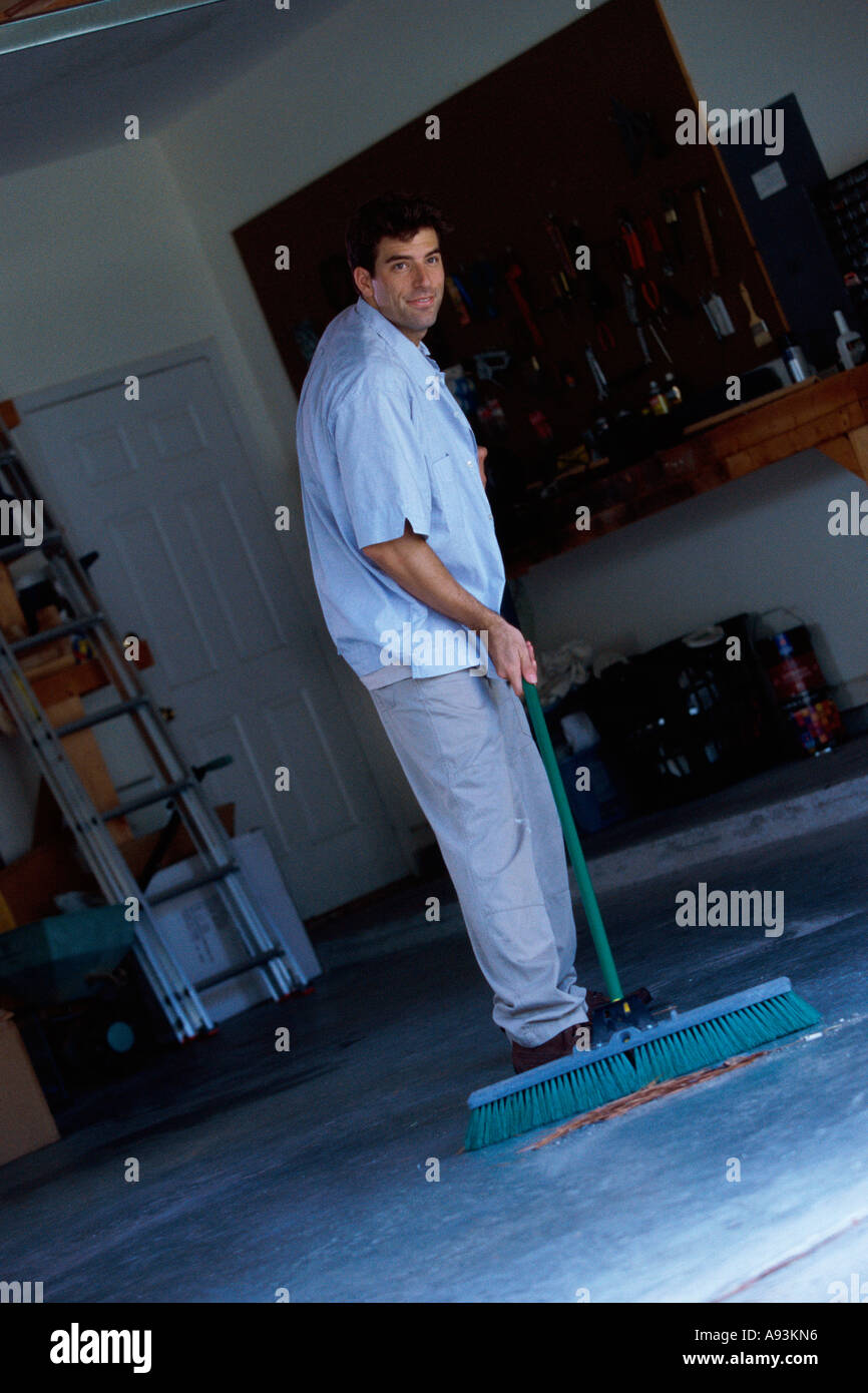 Young man sweeping the floor with a broom Stock Photo - Alamy