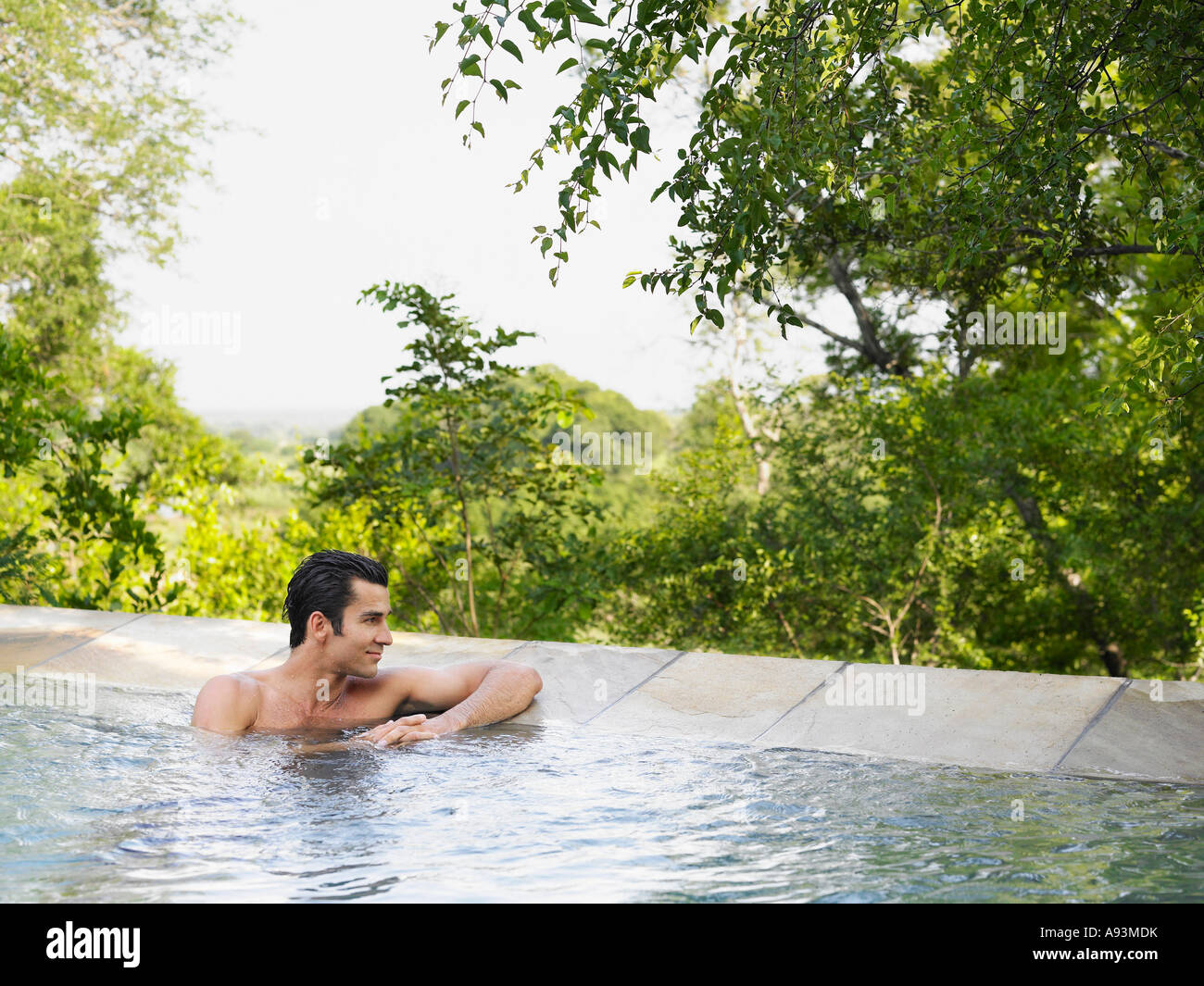 Mid adult man sitting in pool, looking at view Stock Photo - Alamy