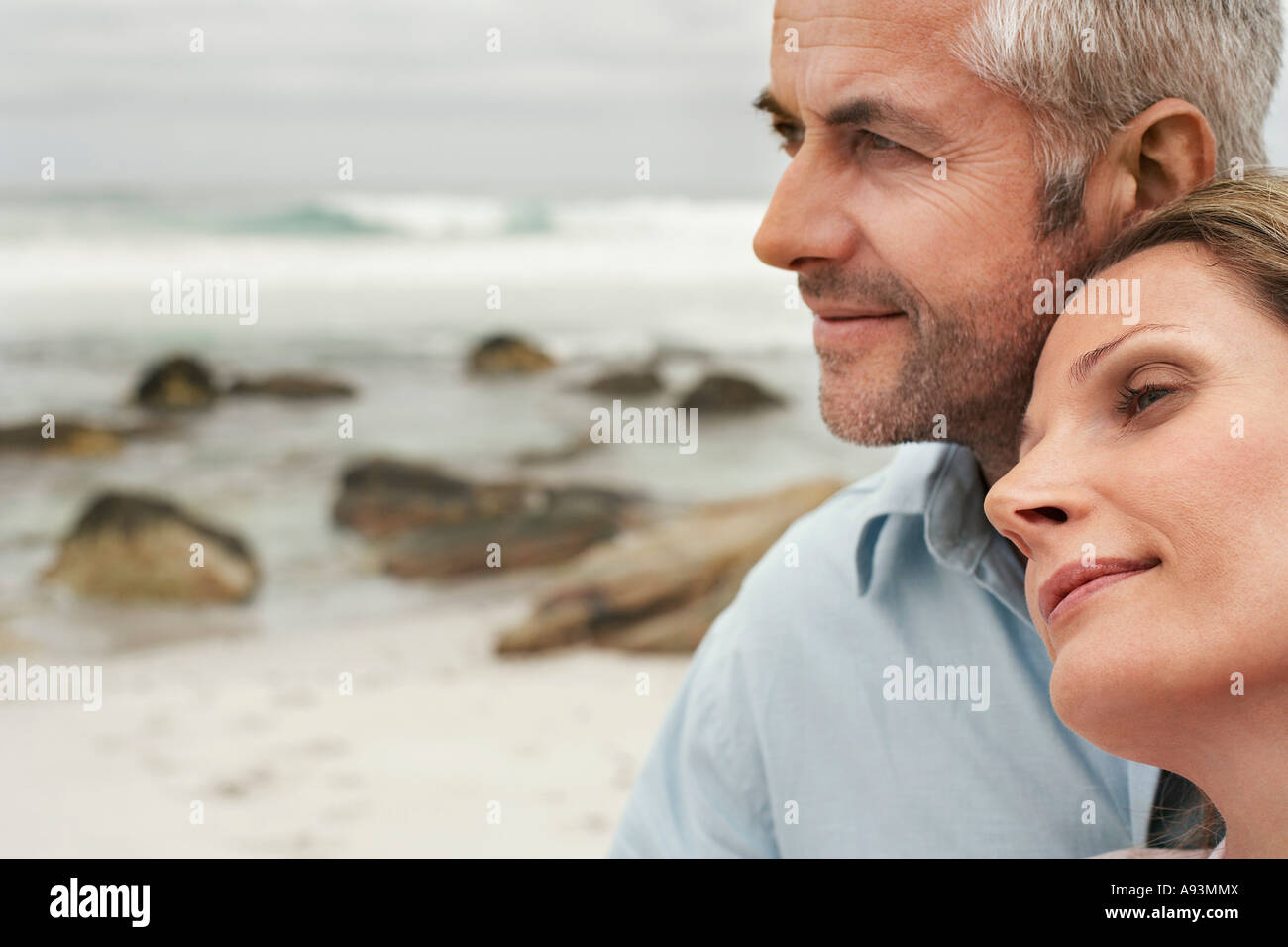 Close up of couple on beach, woman resting her head on man's shoulder ...