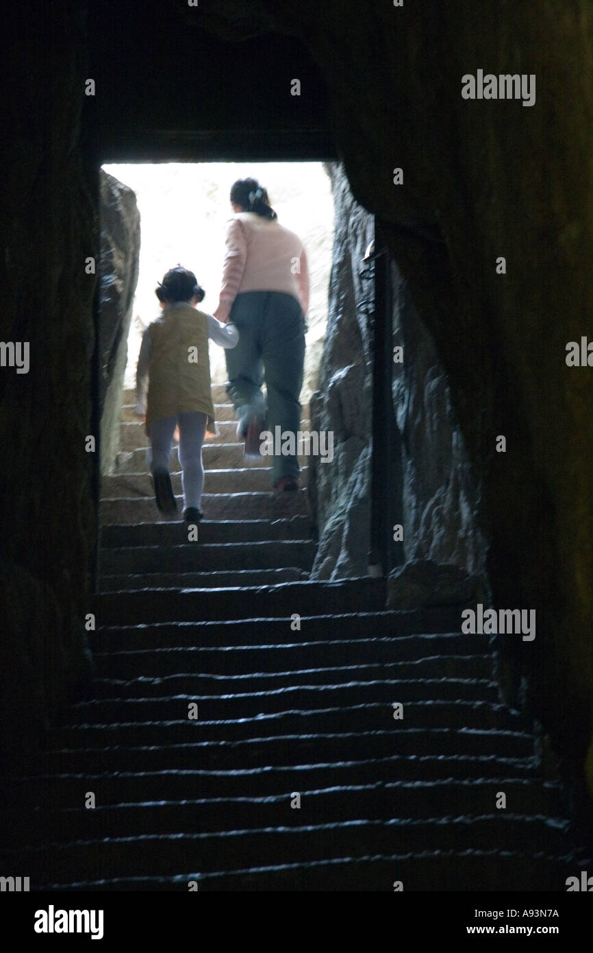 Emerging into the light a woman and a little girl climb steps out of a ...