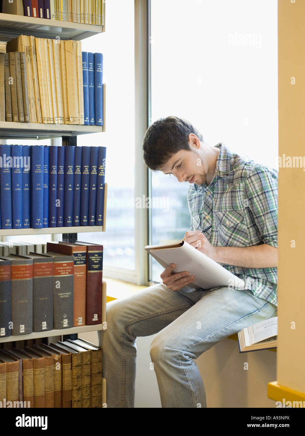 Student sitting on windowsill in library taking notes Stock Photo - Alamy