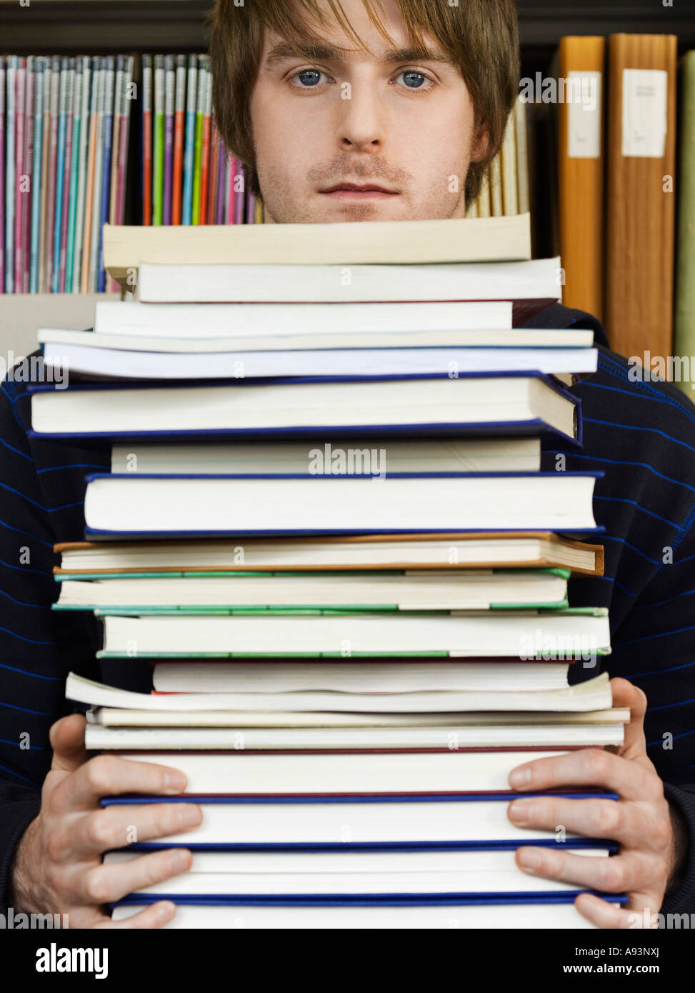 Young man holding pile of books Stock Photo - Alamy