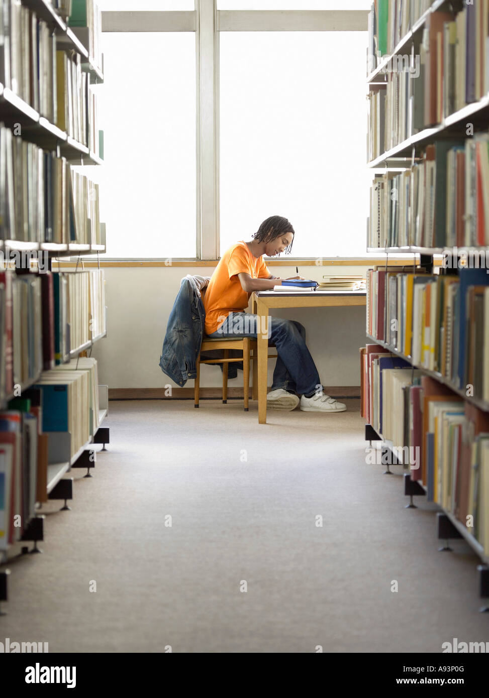 Teenage boy doing homework in library Stock Photo - Alamy