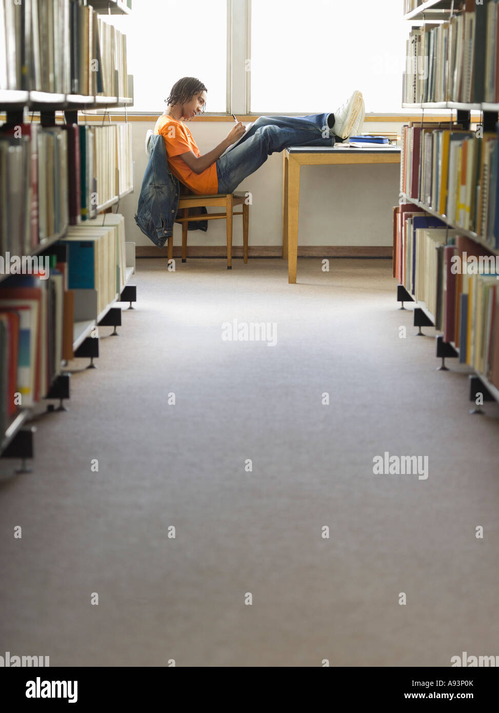 Teenage boy doing homework in library Stock Photo - Alamy