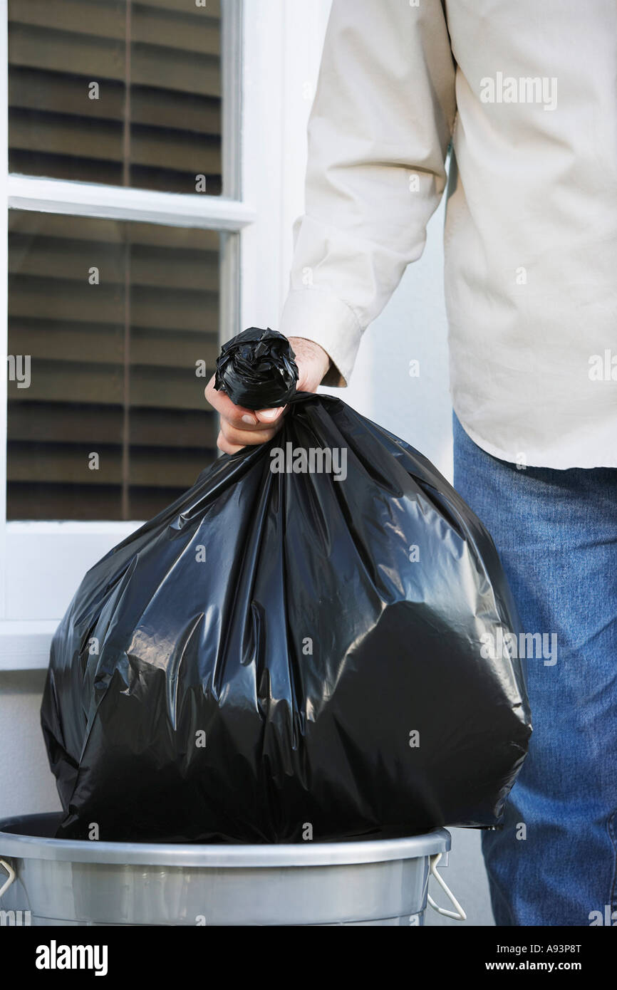 Man putting garbage bag into trash can, mid section Stock Photo - Alamy