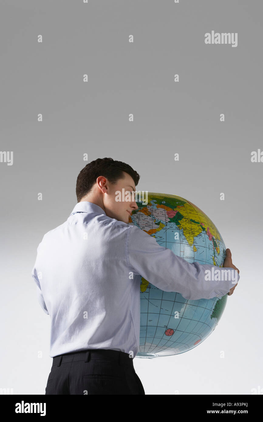 Young adult man with arms around big globe, back view Stock Photo - Alamy