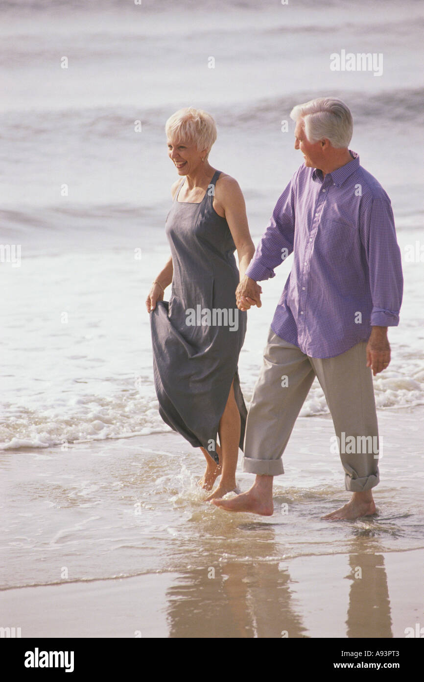 Side profile of a senior couple wading on the beach Stock Photo - Alamy
