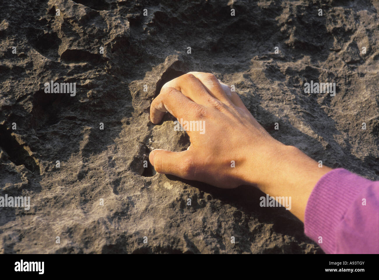 A hand holds on to rock Stock Photo - Alamy