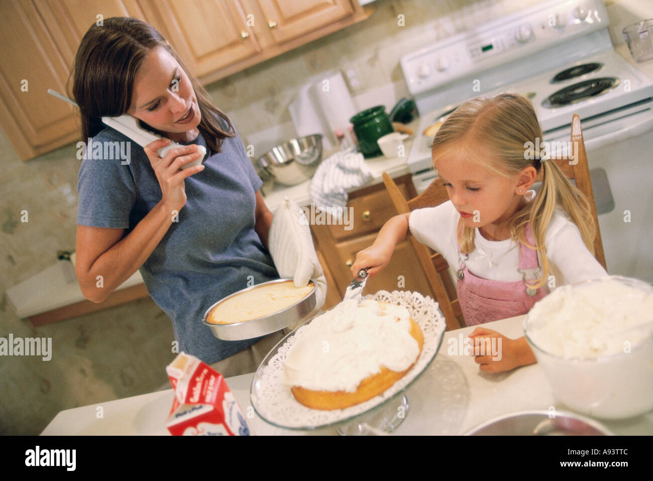 Daughter helping her mother bake a cake Stock Photo - Alamy