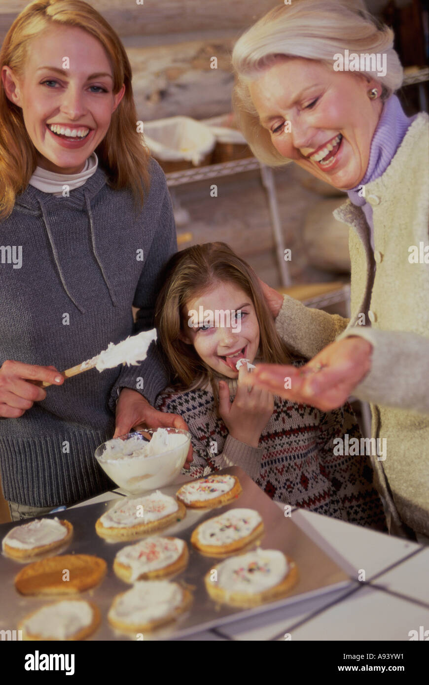 Portrait of a daughter tasting cookies being prepared by her mother and ...