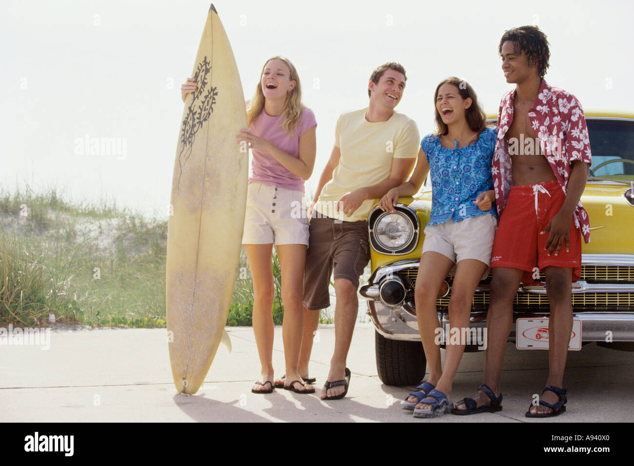 Two teenage couples leaning against a car Stock Photo - Alamy