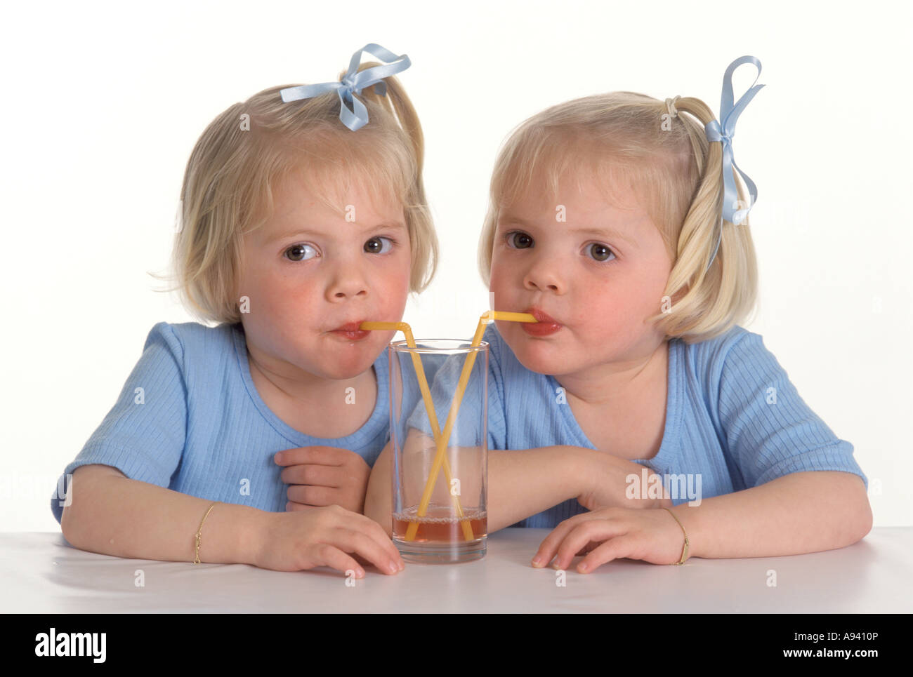 Blond twin girls drinking lemonade together Stock Photo - Alamy