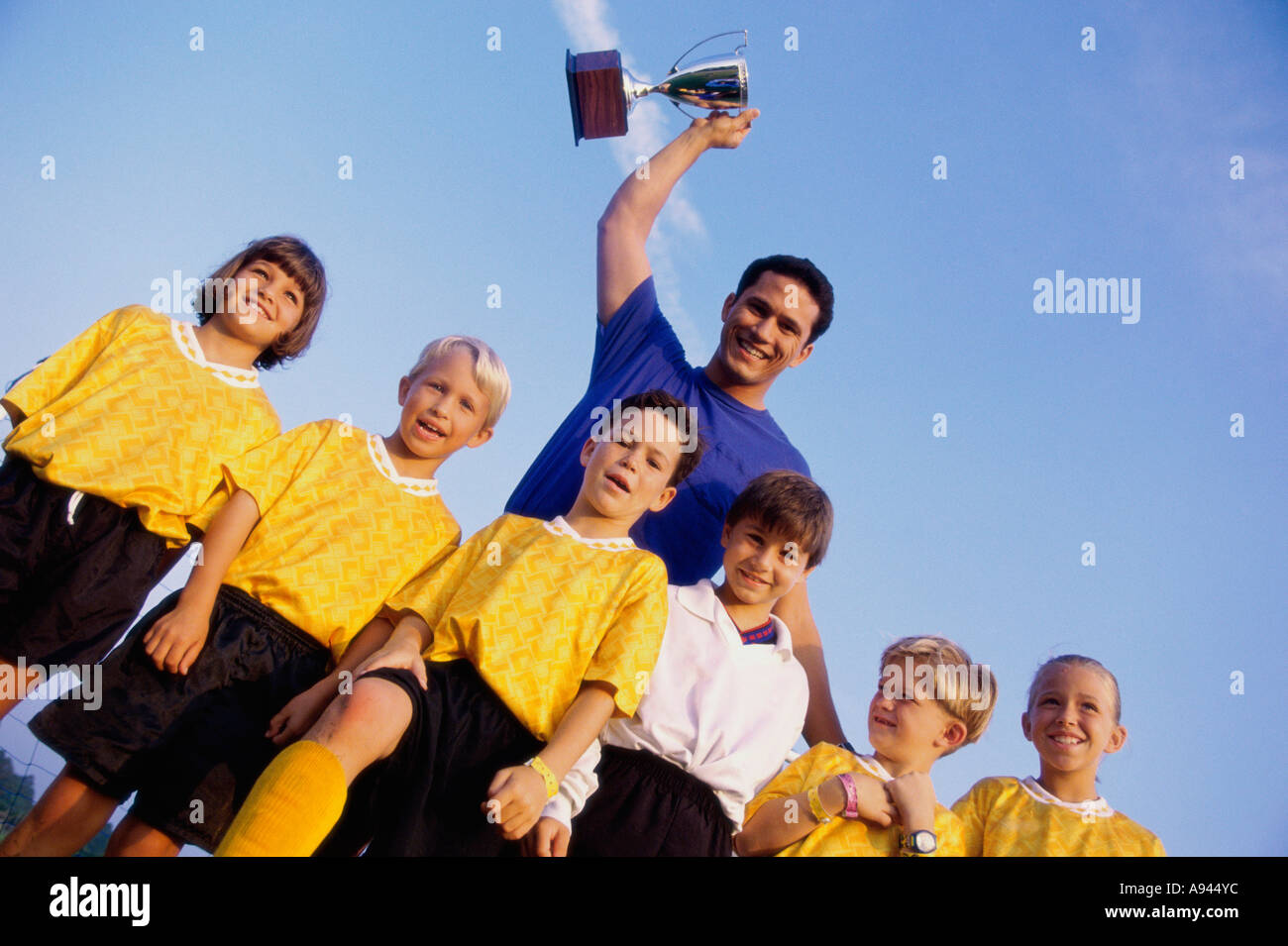Low angle view of a sports team with their coach standing behind them ...