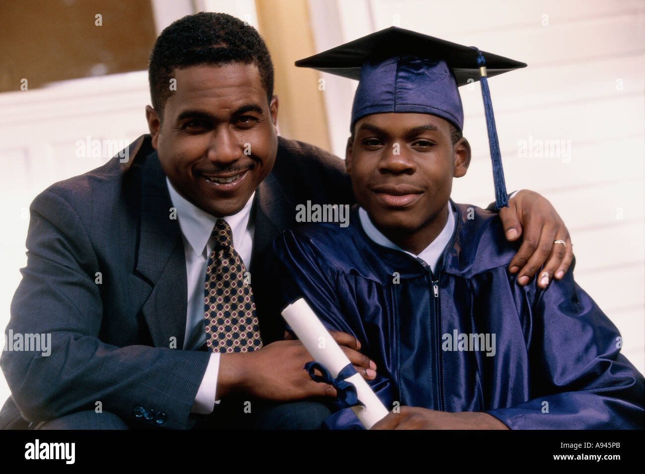 Portrait of a teenage graduate sitting with his father Stock Photo - Alamy
