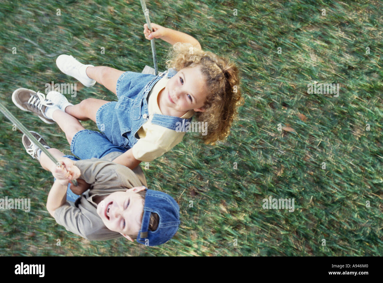 High angle view of a boy and girl swinging on a swing Stock Photo - Alamy