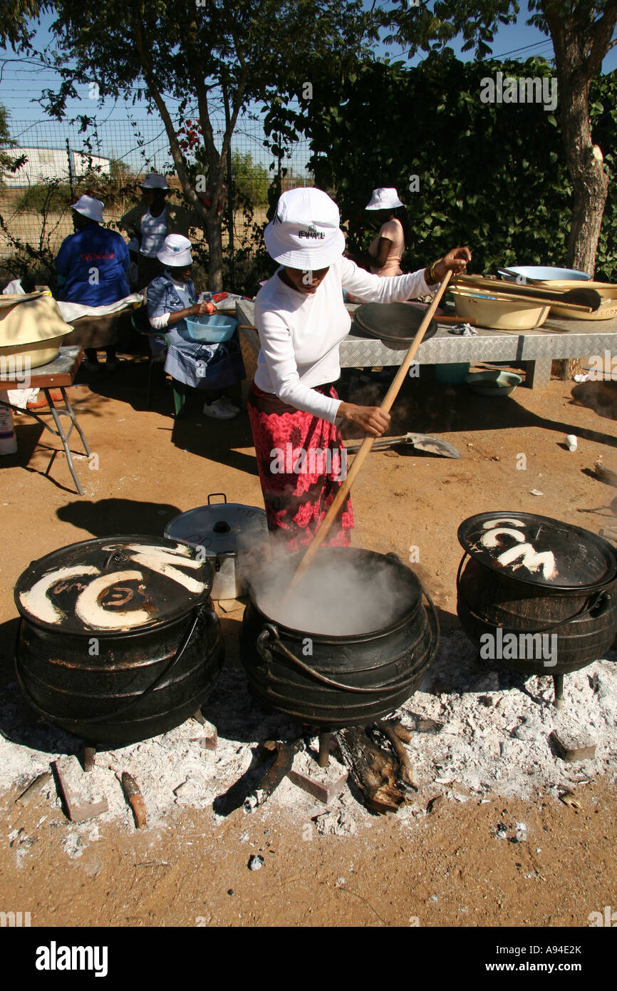 Traditional food being prepared in a row of three legged iron cooking ...