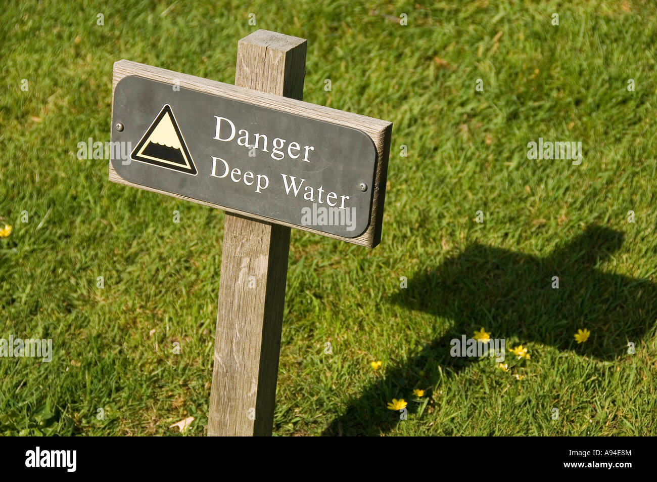 Close up of Danger deep water warning sign with cross shadow England UK ...