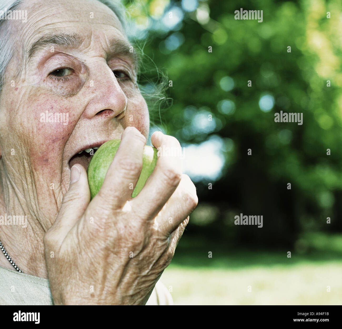 mature woman biting into an apple outside Stock Photo - Alamy
