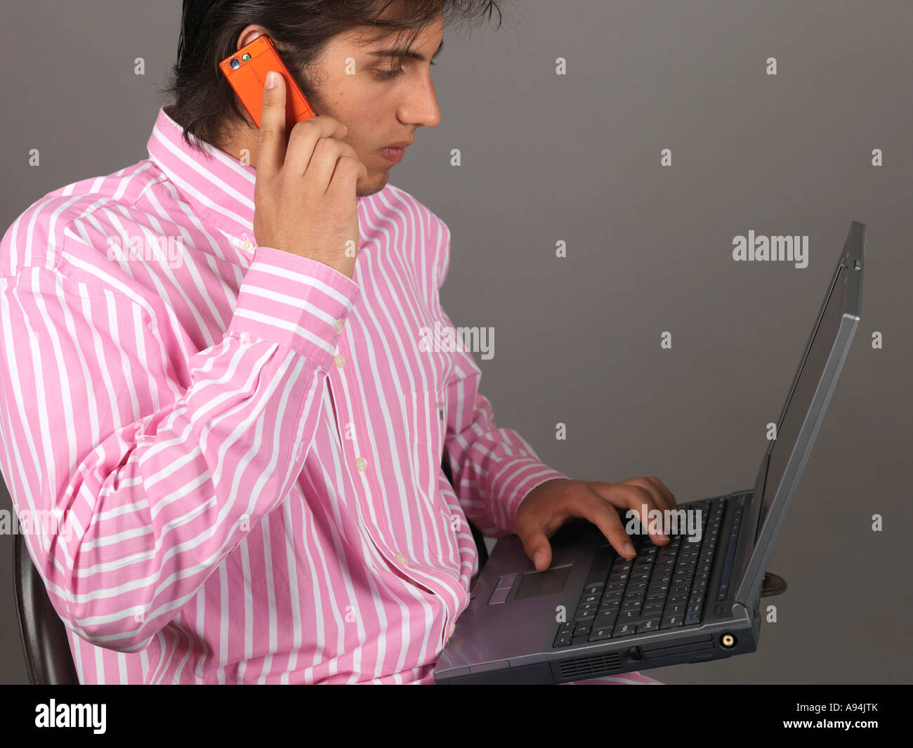 Young Man Working Remotely On A Laptop Computer And A Retro Mobile Cell ...