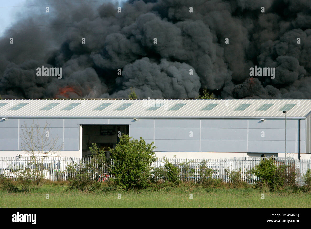 thick plume of black grey smoke and flames rising from industrial ...