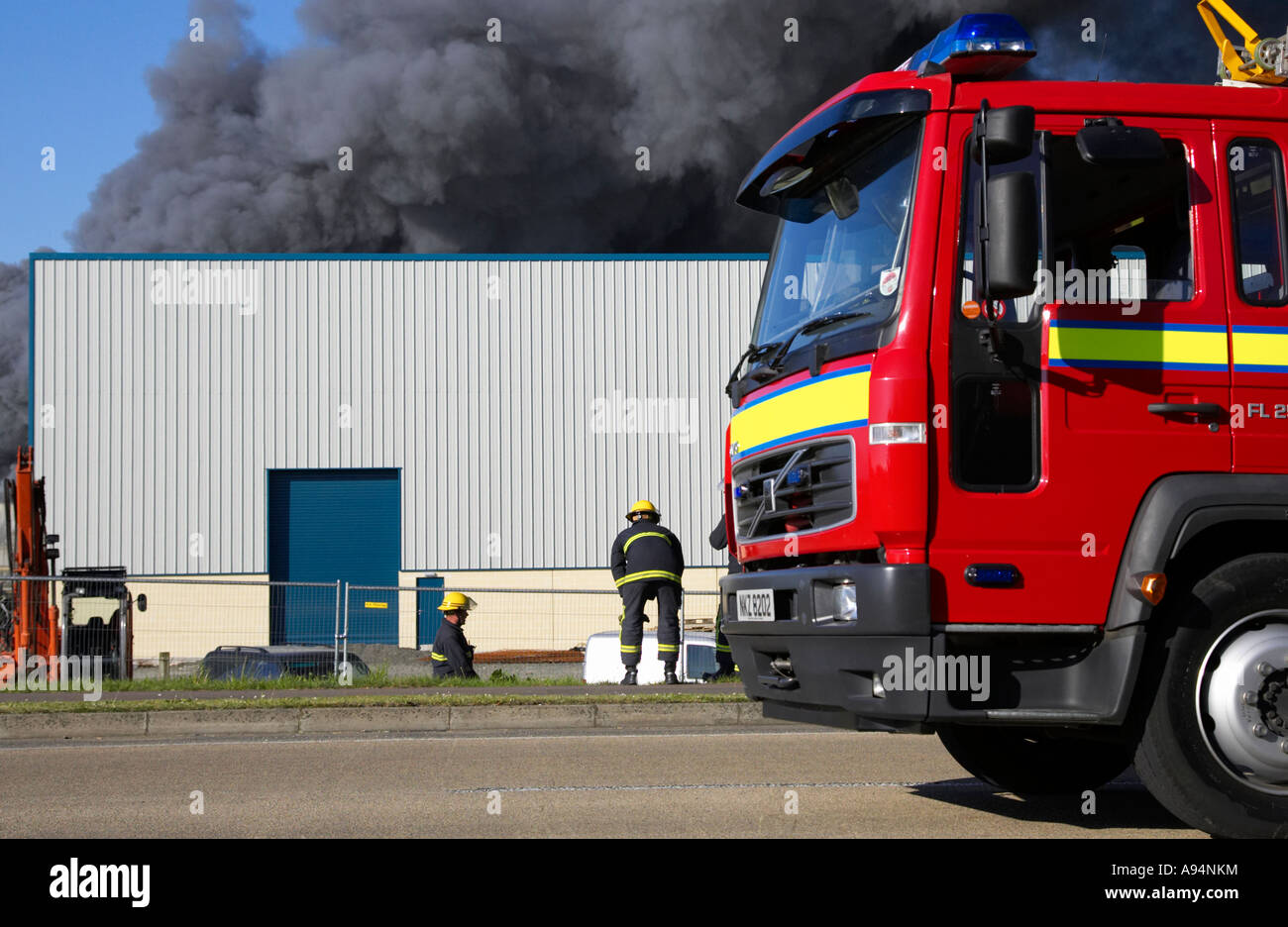 cab of fire engine with firefighters outside beneath column of smoke at ...