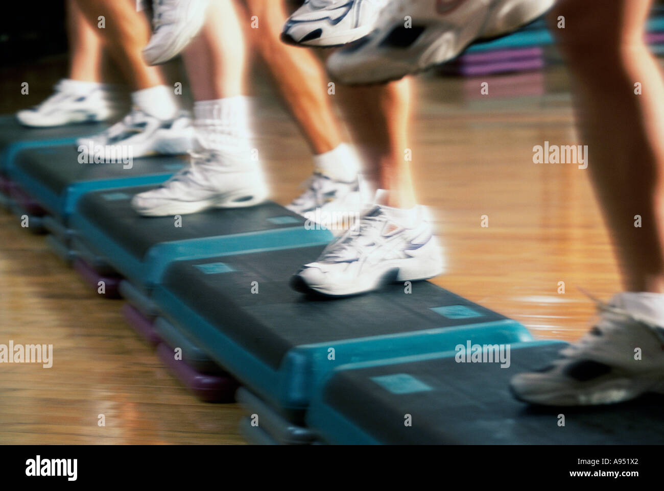 Low section view of a group of people doing step aerobics in a gym ...