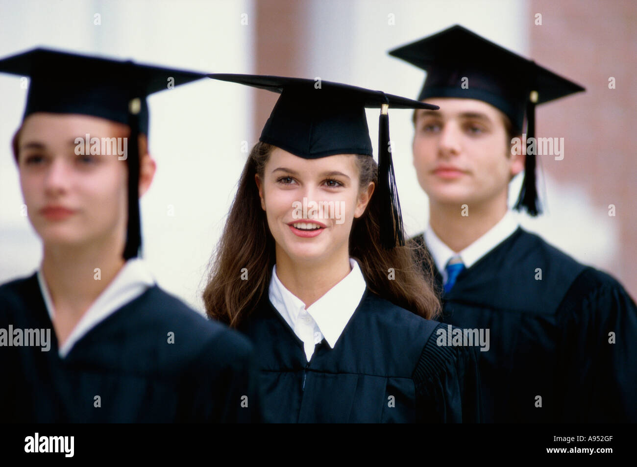 Portrait of three young graduates standing in a row Stock Photo - Alamy