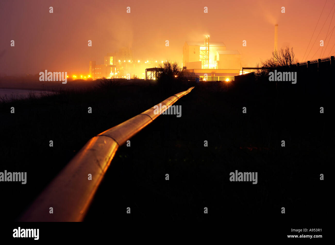 Pipeline going into factory at night Stock Photo - Alamy