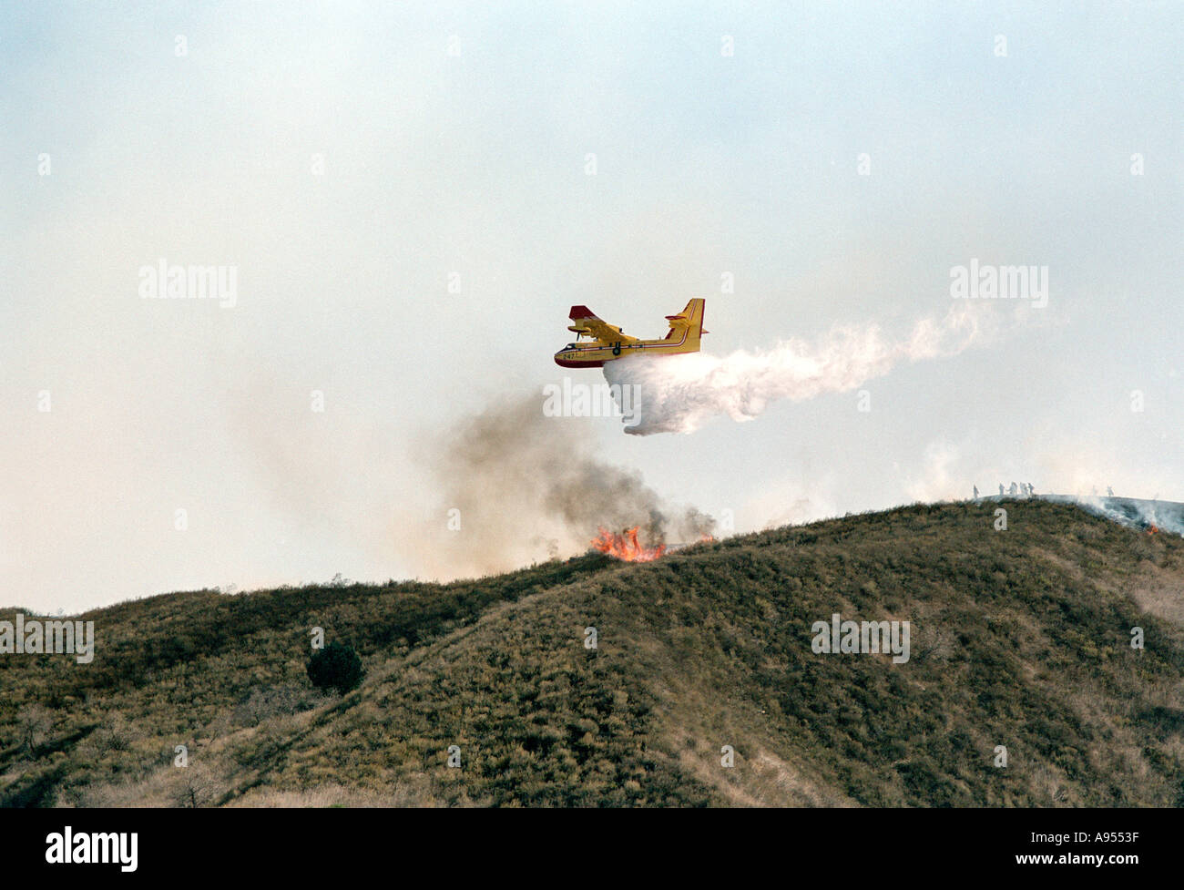 Firefighting airplane drops water on a brush fire in California as ...