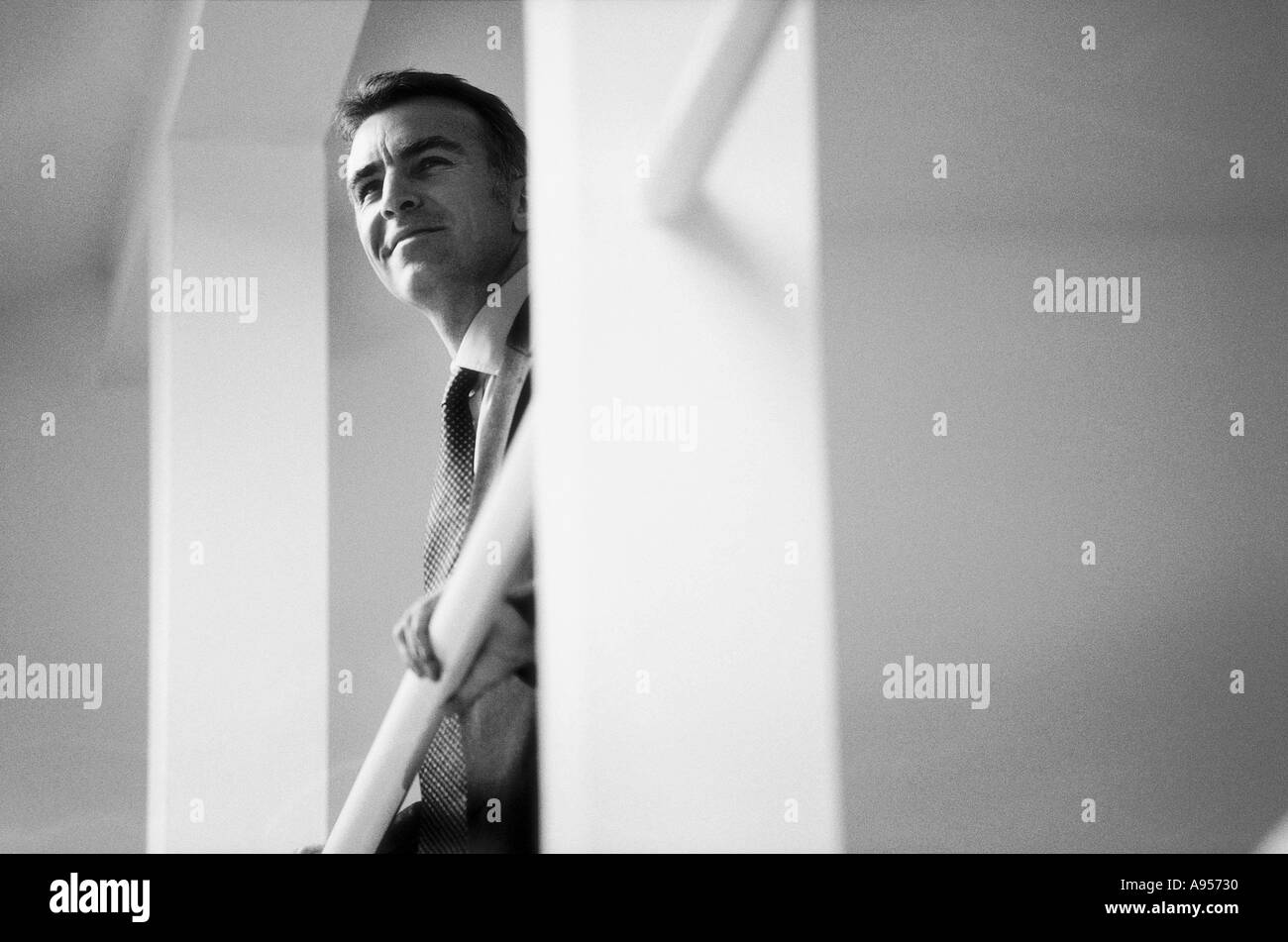 Photograph of man looking over balcony Stock Photo - Alamy