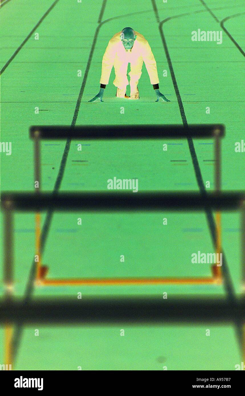 Photograph of suited man on starting blocks of hurdle running track ...