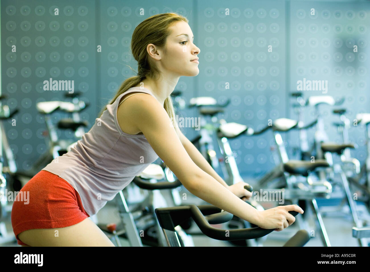 Woman riding exercise bike Stock Photo - Alamy