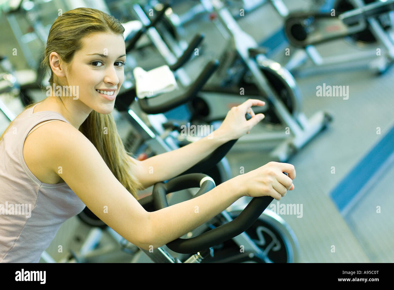 Woman riding exercise bike Stock Photo - Alamy