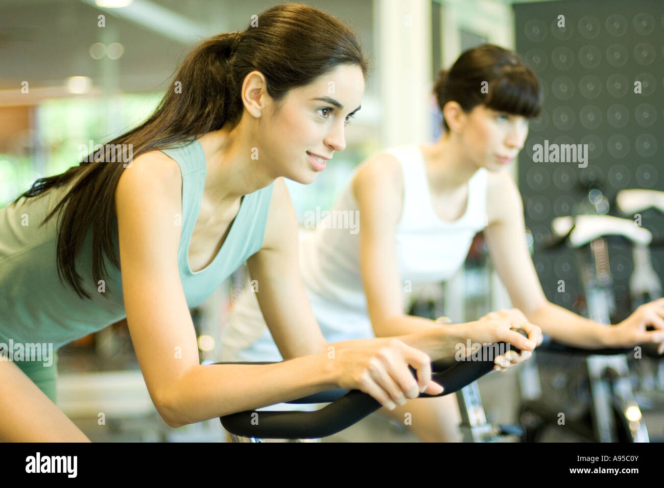 Women riding exercise bikes Stock Photo - Alamy
