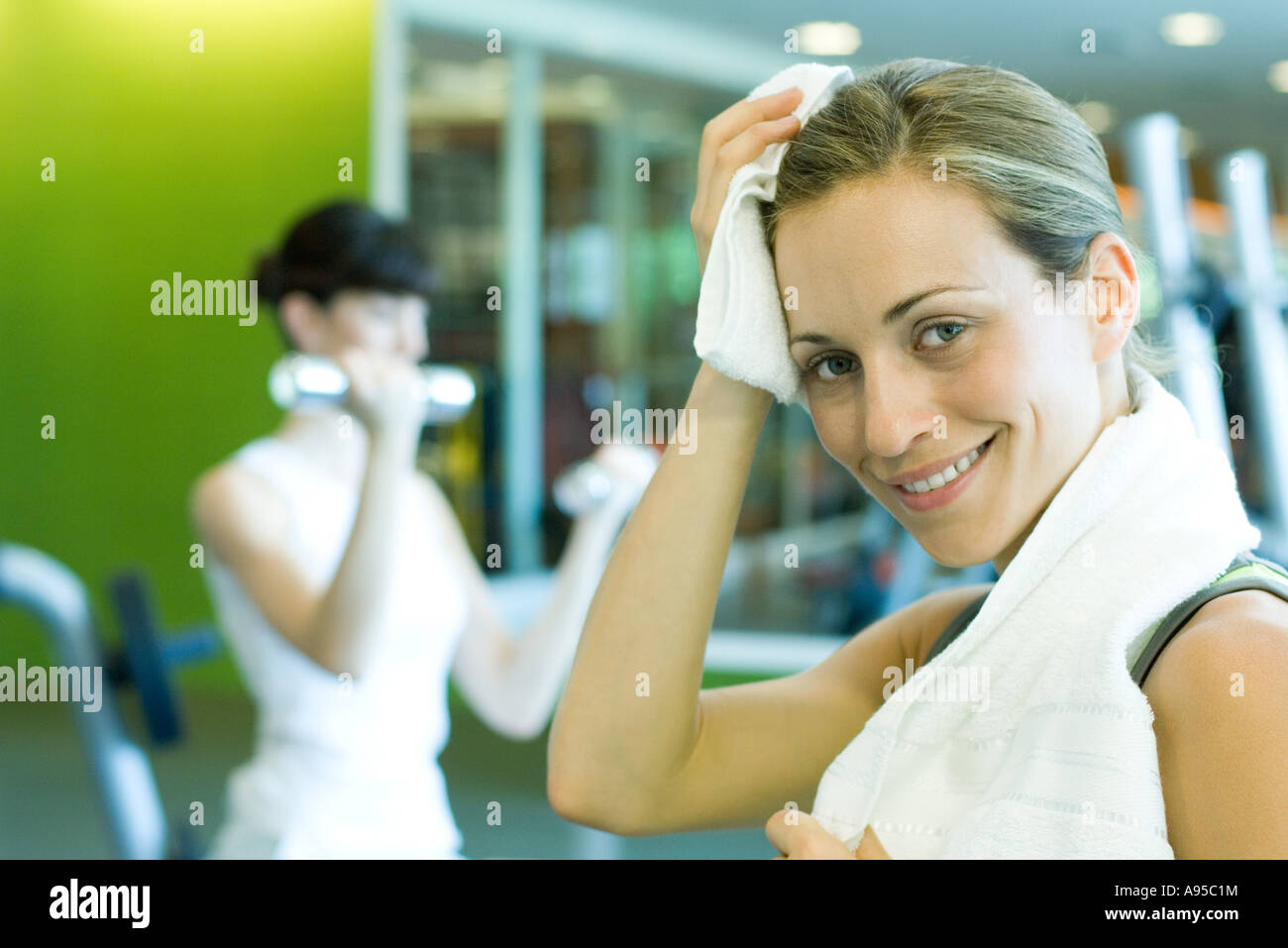 Woman in weight room, wiping forehead, smiling at camera Stock Photo ...