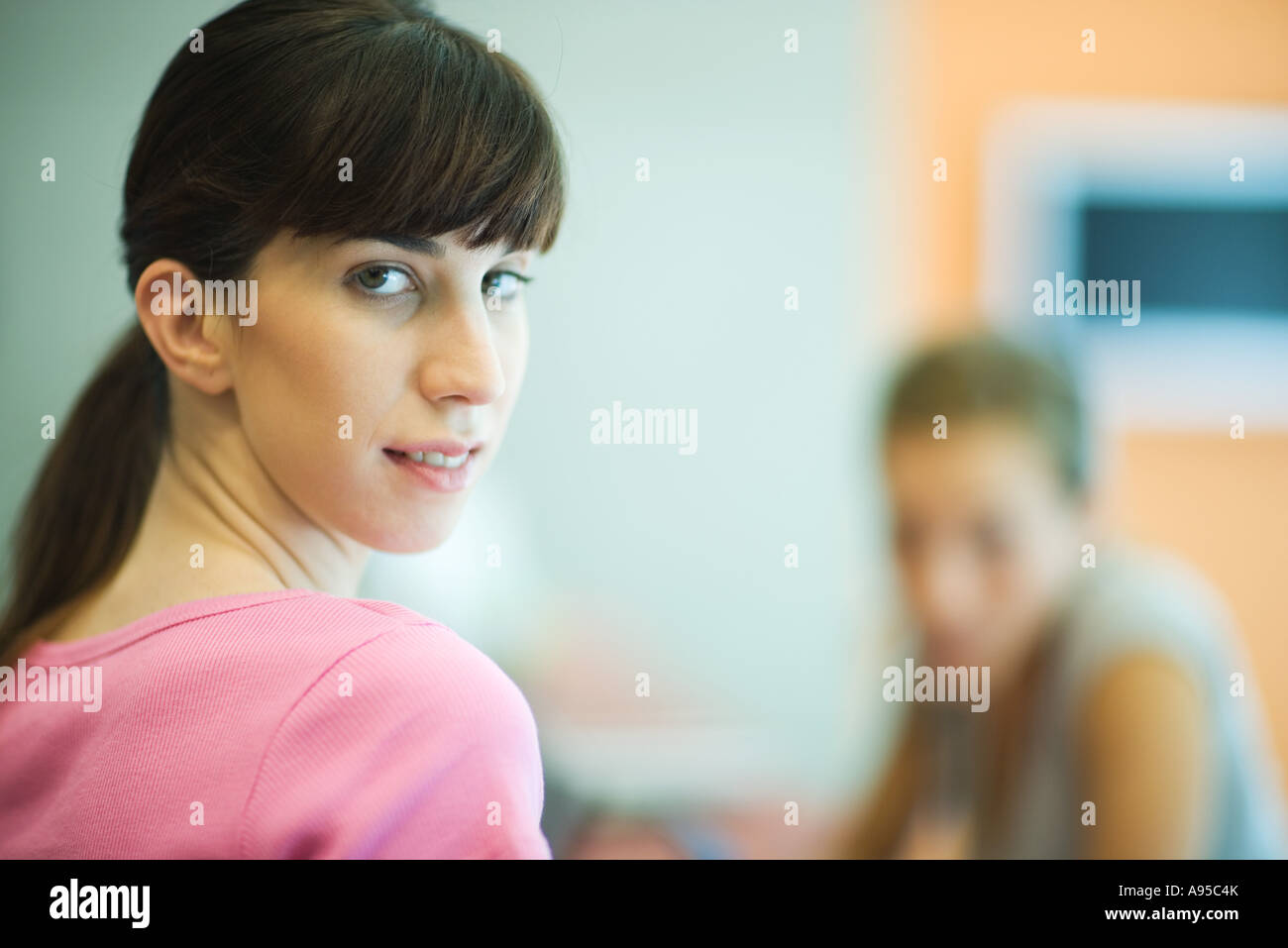Young woman looking over shoulder at camera Stock Photo - Alamy