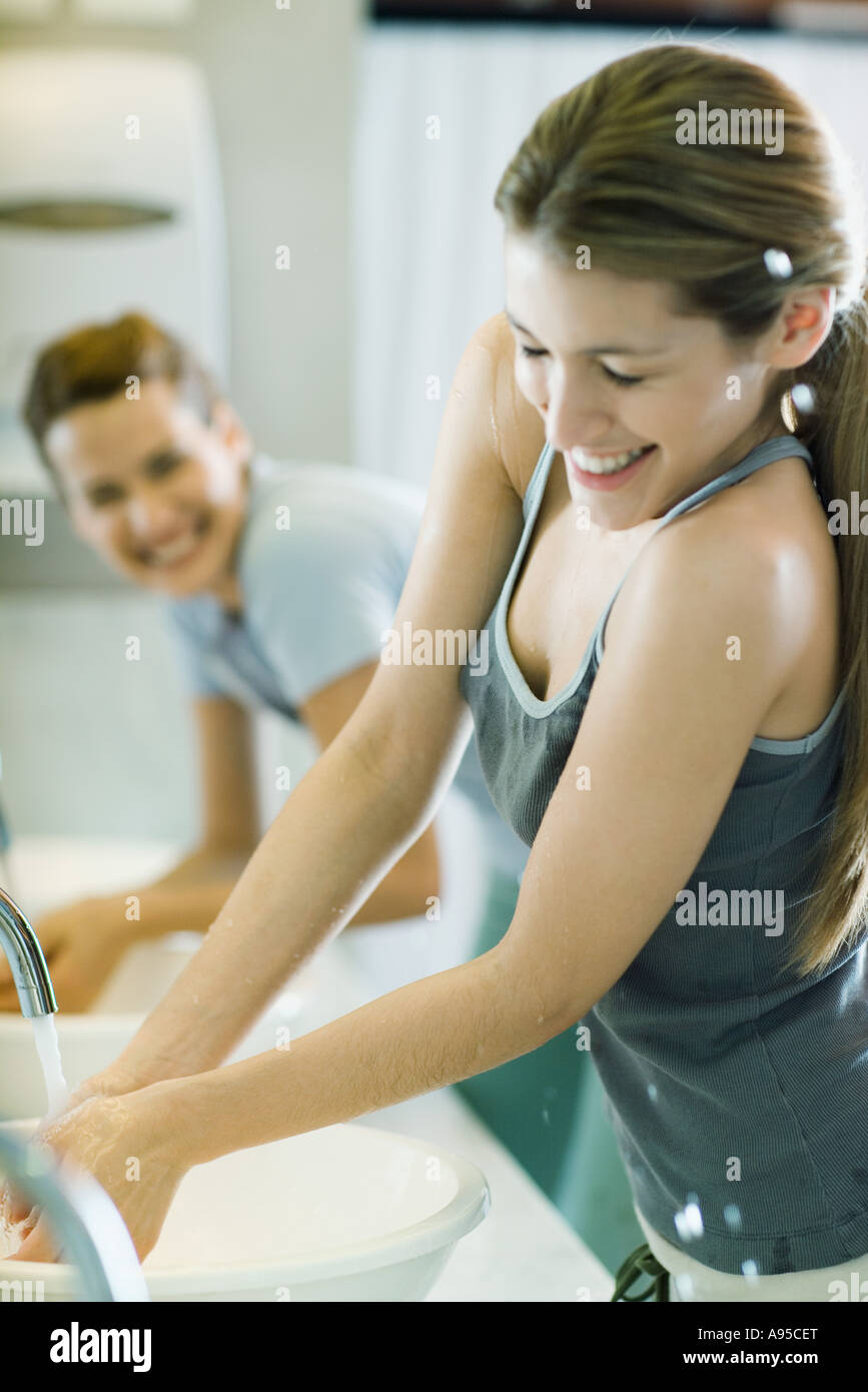 Two women washing hands in sinks, one getting splashed Stock Photo - Alamy